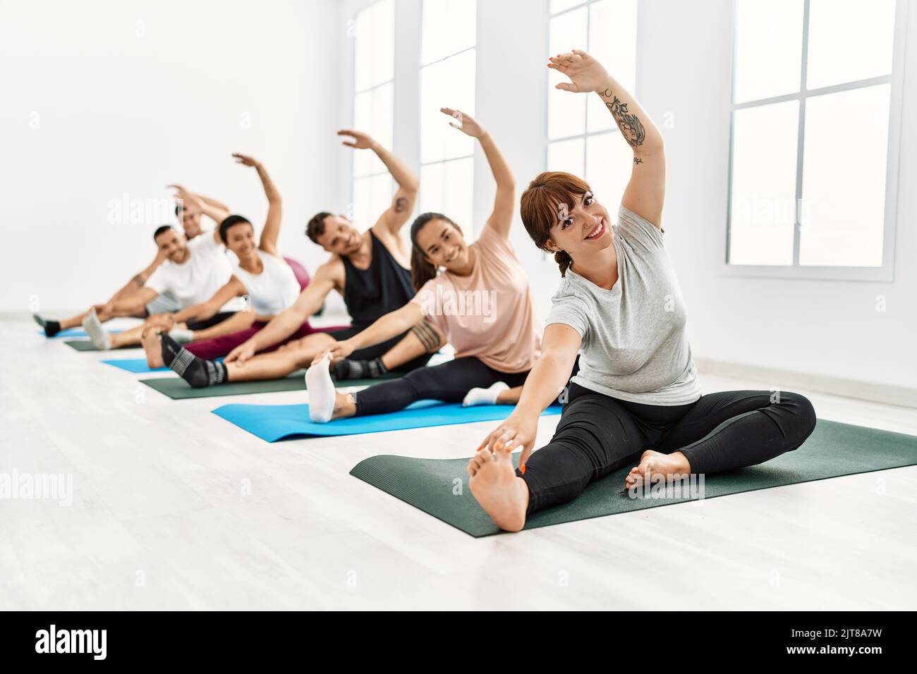 Group of young sporty people smiling happy stretching at sport center ...