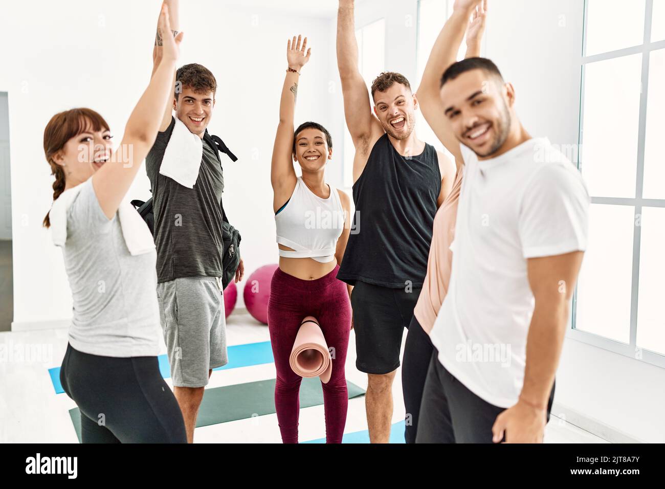 Group of young sporty people smiling happy with hands raised up at ...
