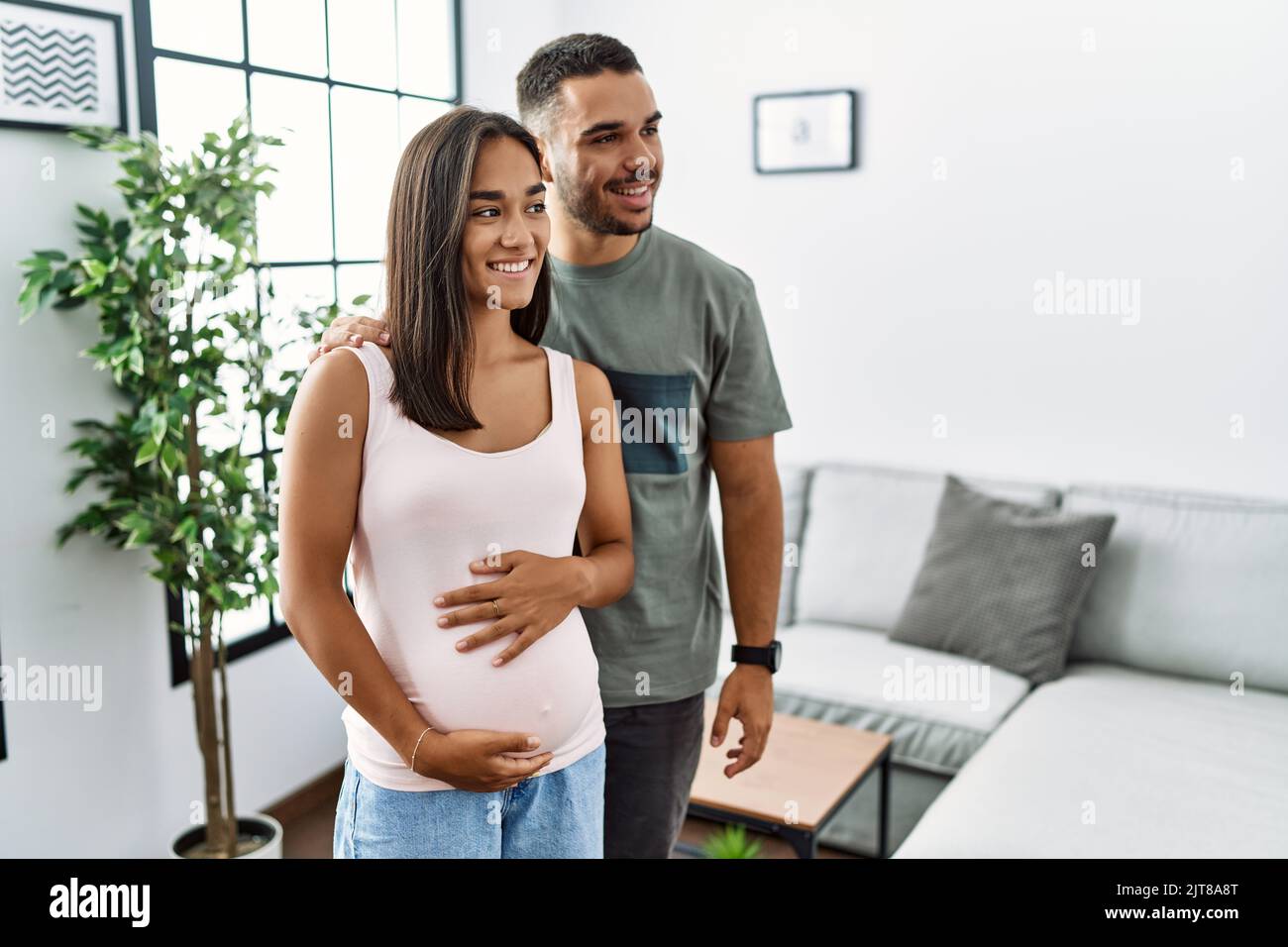 Young interracial couple expecting a baby, touching pregnant belly ...