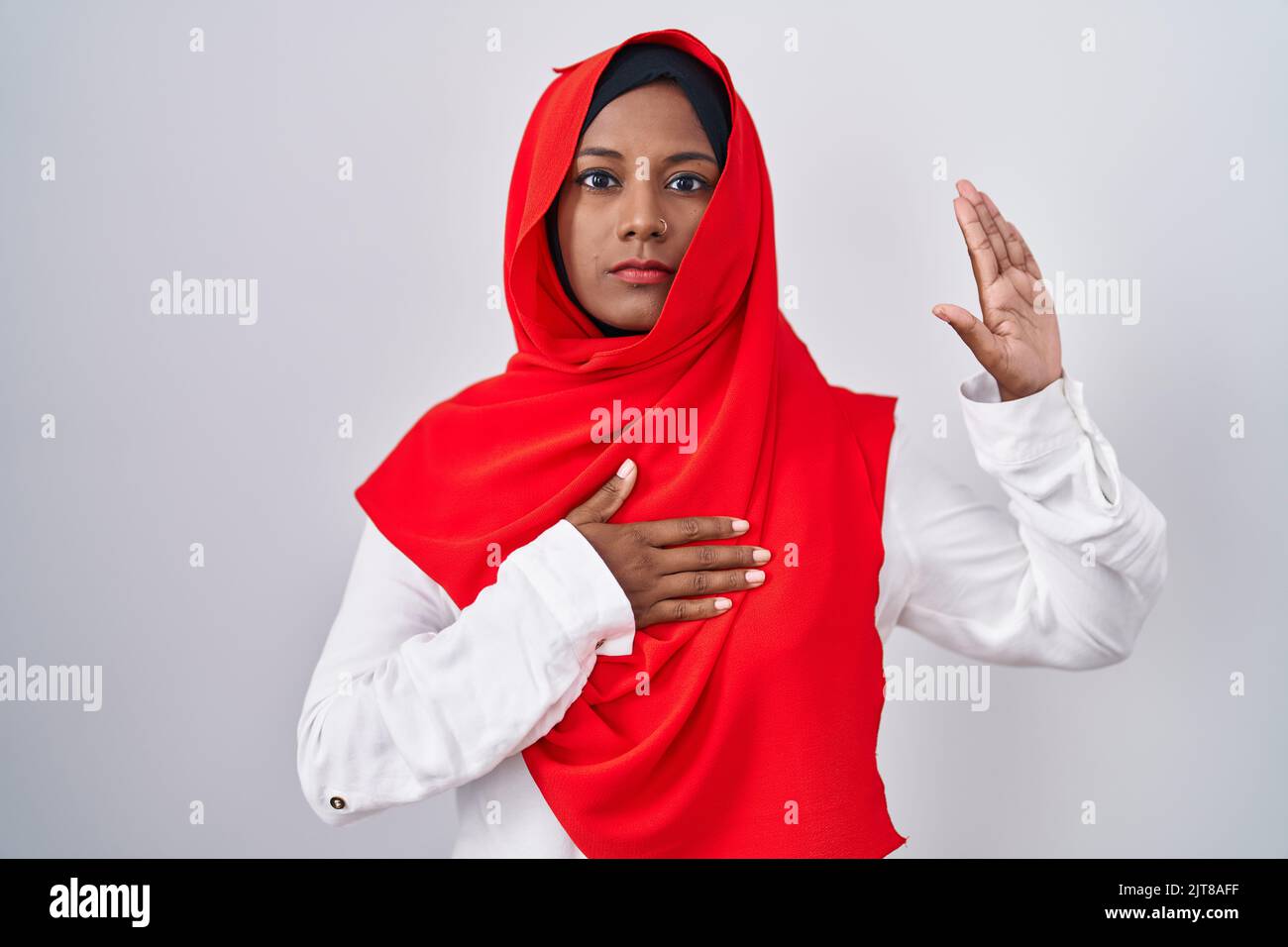 Young arab woman wearing traditional islamic hijab scarf swearing with ...