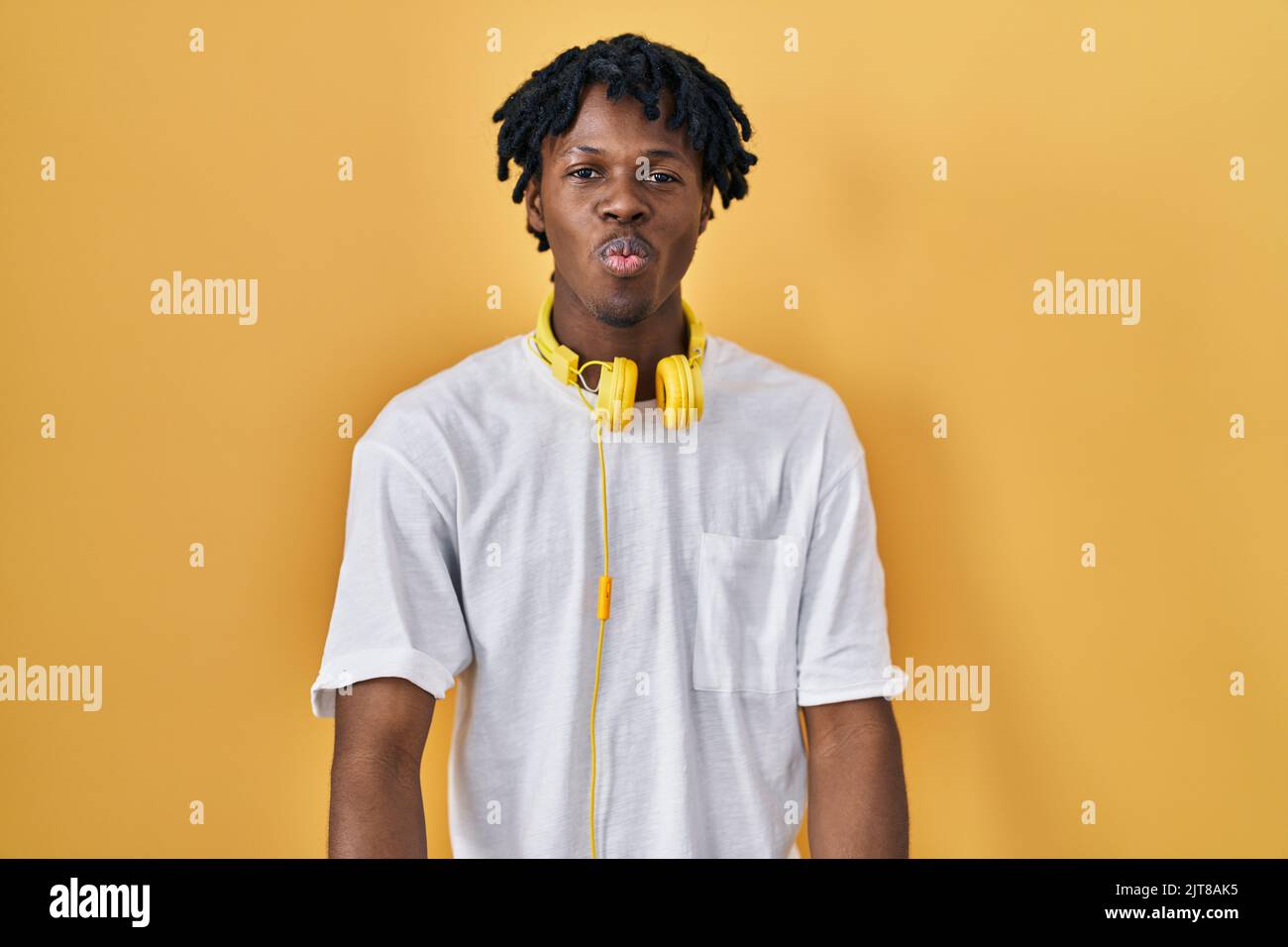 Young african man with dreadlocks standing over yellow background ...