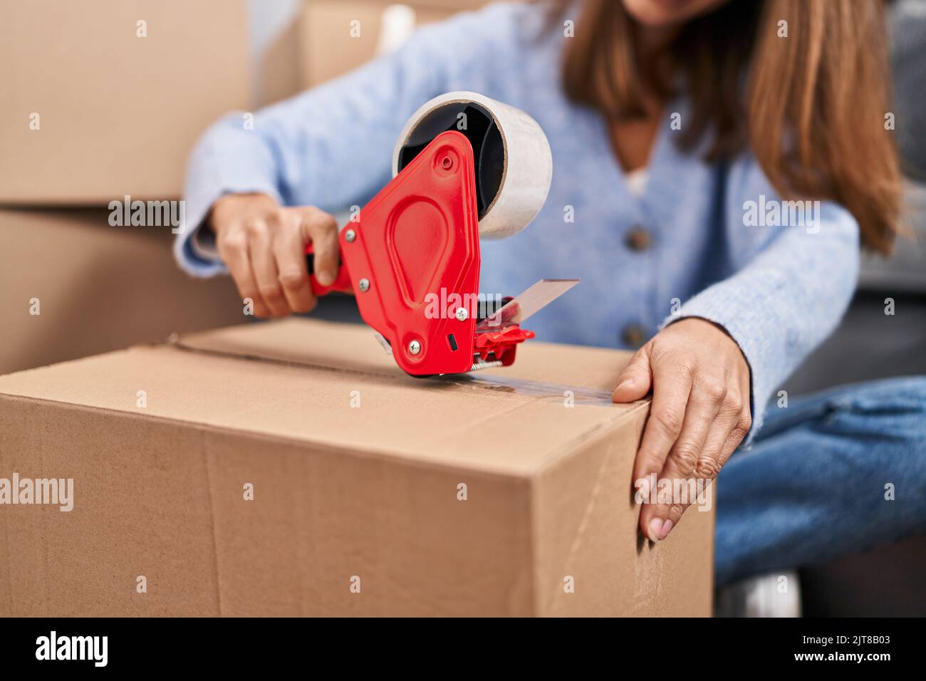 Young woman packing cardboard box at new home Stock Photo - Alamy