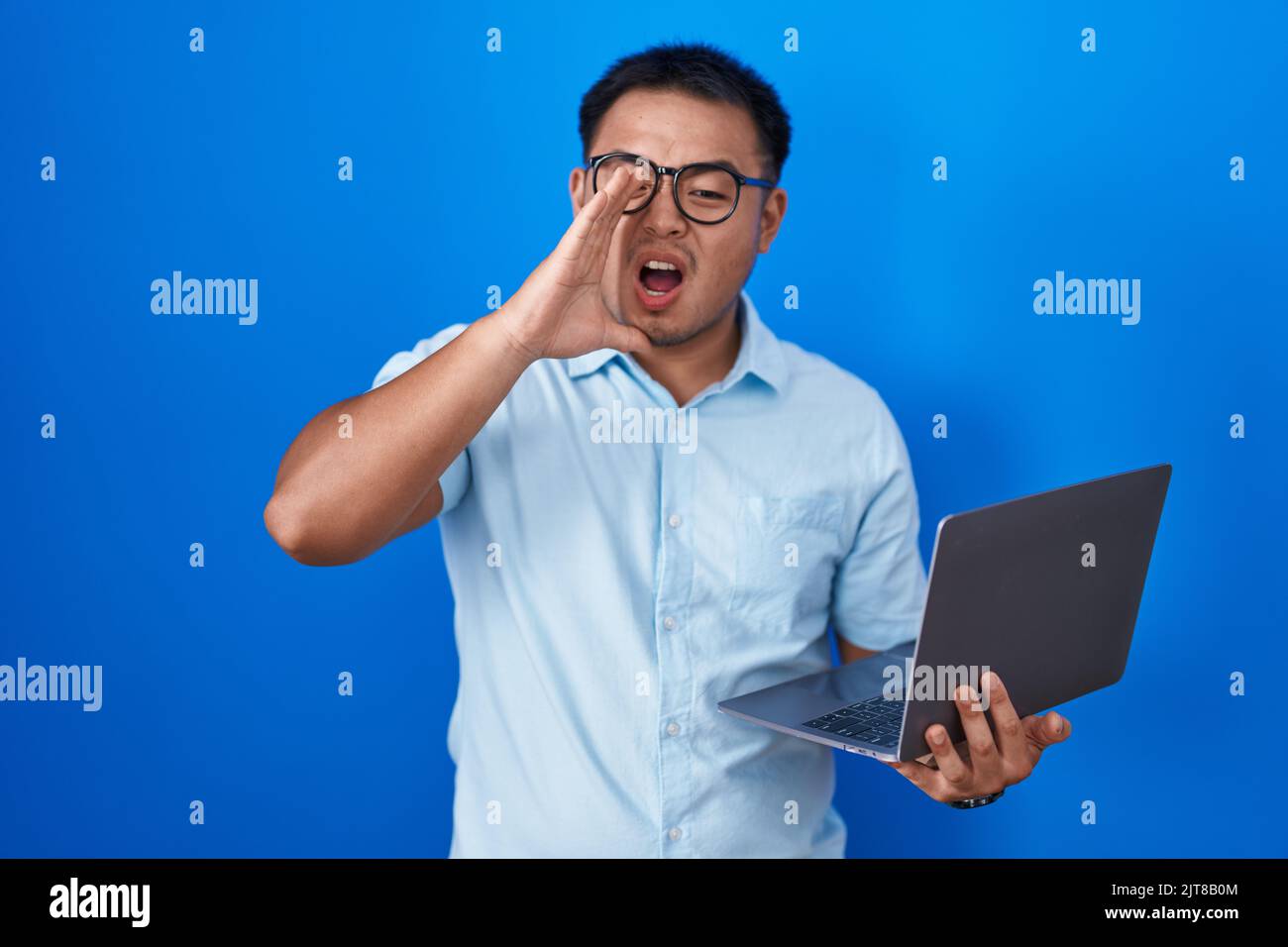 Chinese young man using computer laptop shouting and screaming loud to ...