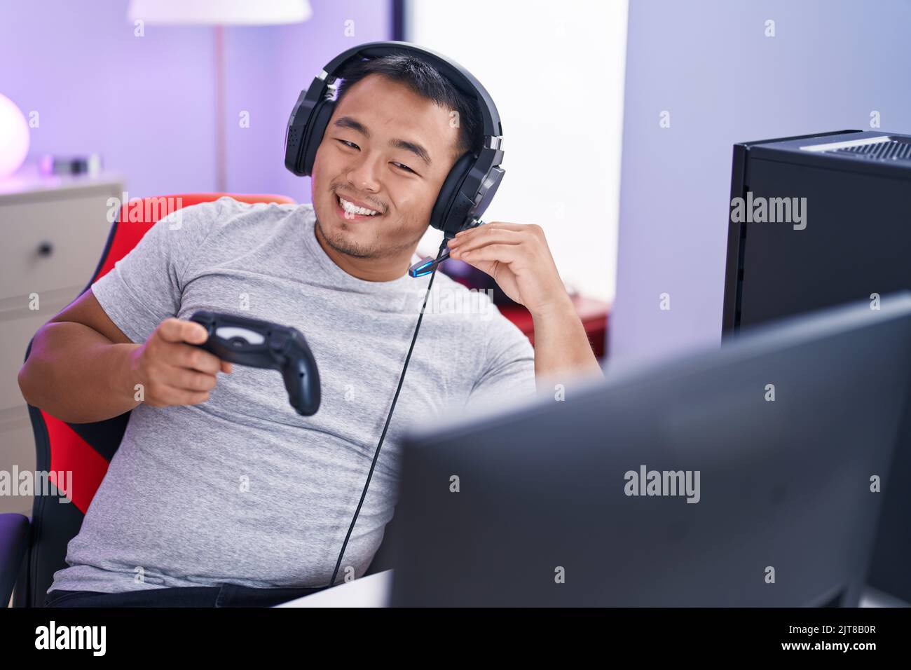 Young chinese man streamer playing video game using joystick at gaming ...