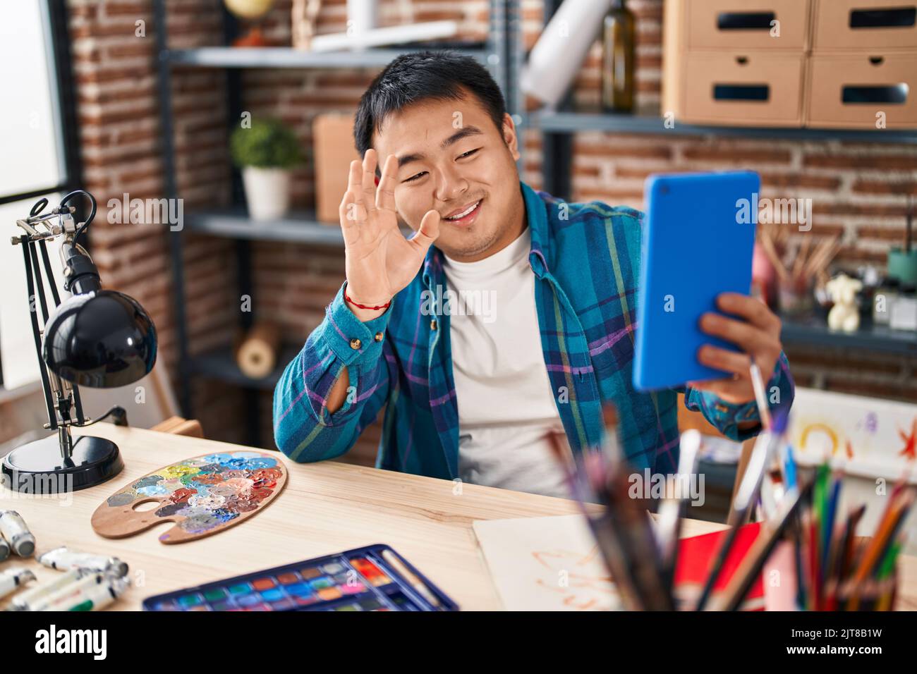 Young chinese man artist having video call at art studio Stock Photo ...