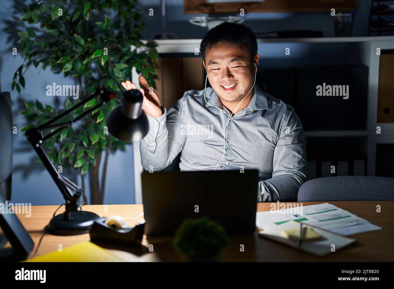 Young chinese man working using computer laptop at night smiling ...