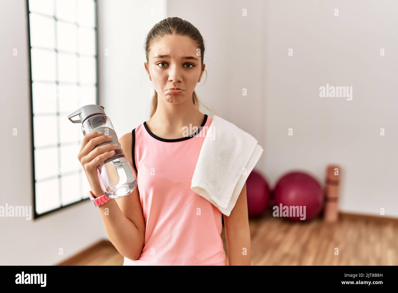 Young brunette teenager wearing sportswear holding water bottle ...