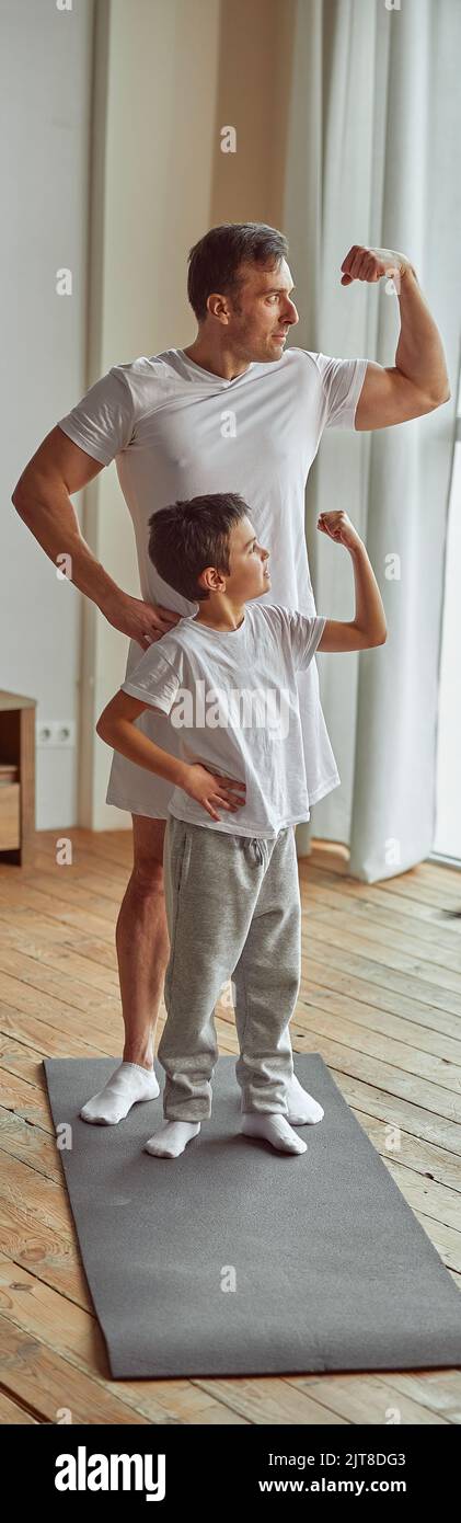 Sporty father and son demonstrating muscles indoors Stock Photo - Alamy