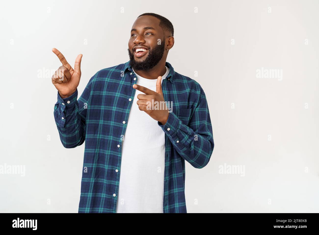 Young amazed African American pointing his finger at white background ...