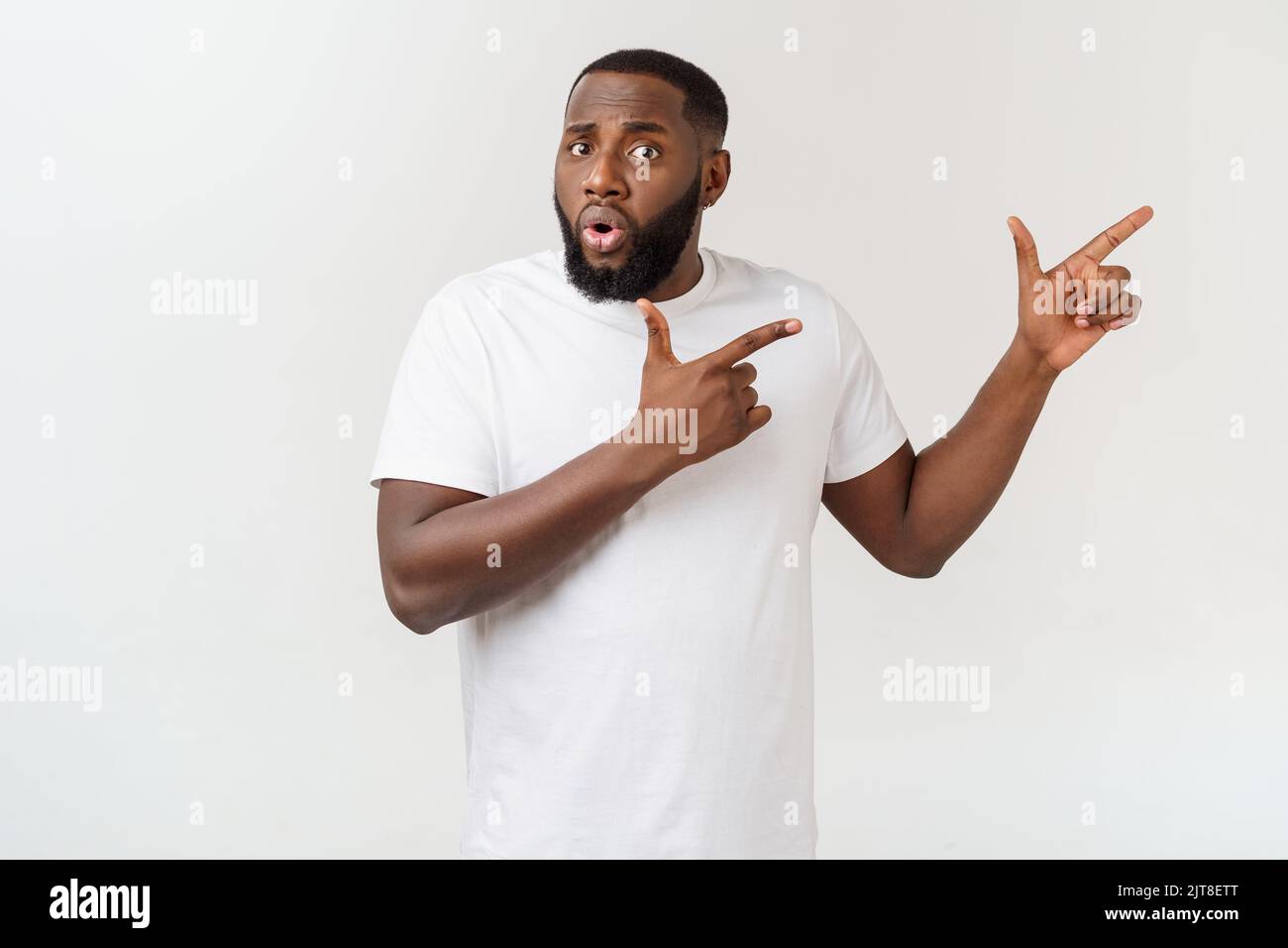 Young amazed African American pointing his finger at white background ...