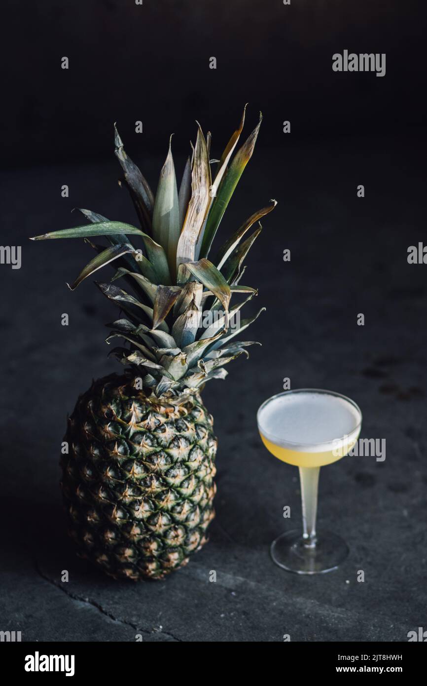 tropical yellow cocktail in hollow stem coupe glass with pineapple ...