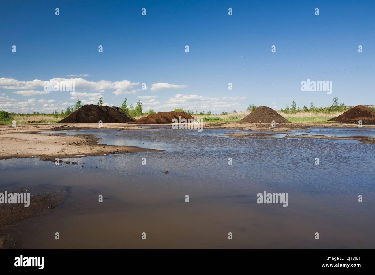 Mounds of brown stacked topsoil after a heavy rainfall in a commercial ...