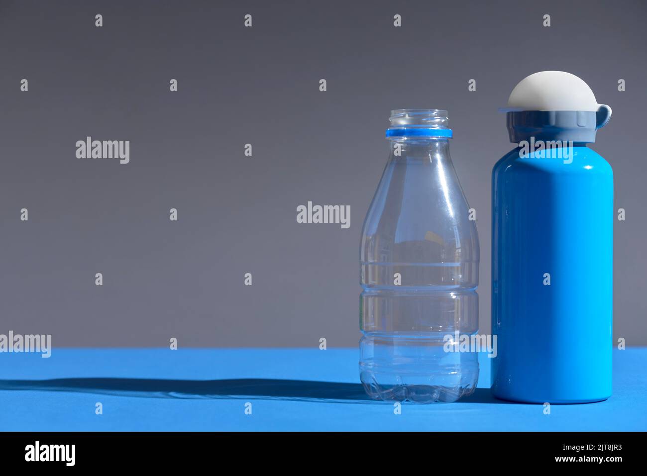 Pair of bottles, a plastic transparent disposable one and a blue metal ...