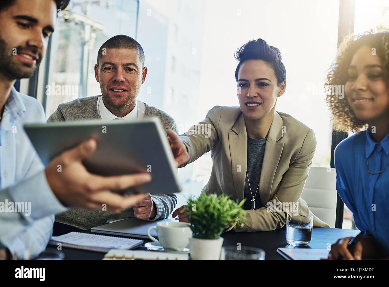 Giving her input. a group of colleagues using a tablet while meeting in ...