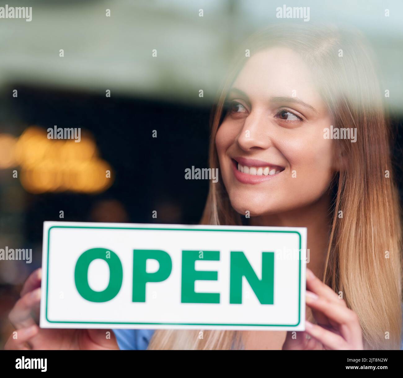 Waiting for the customers. an attractive young woman opening up her ...