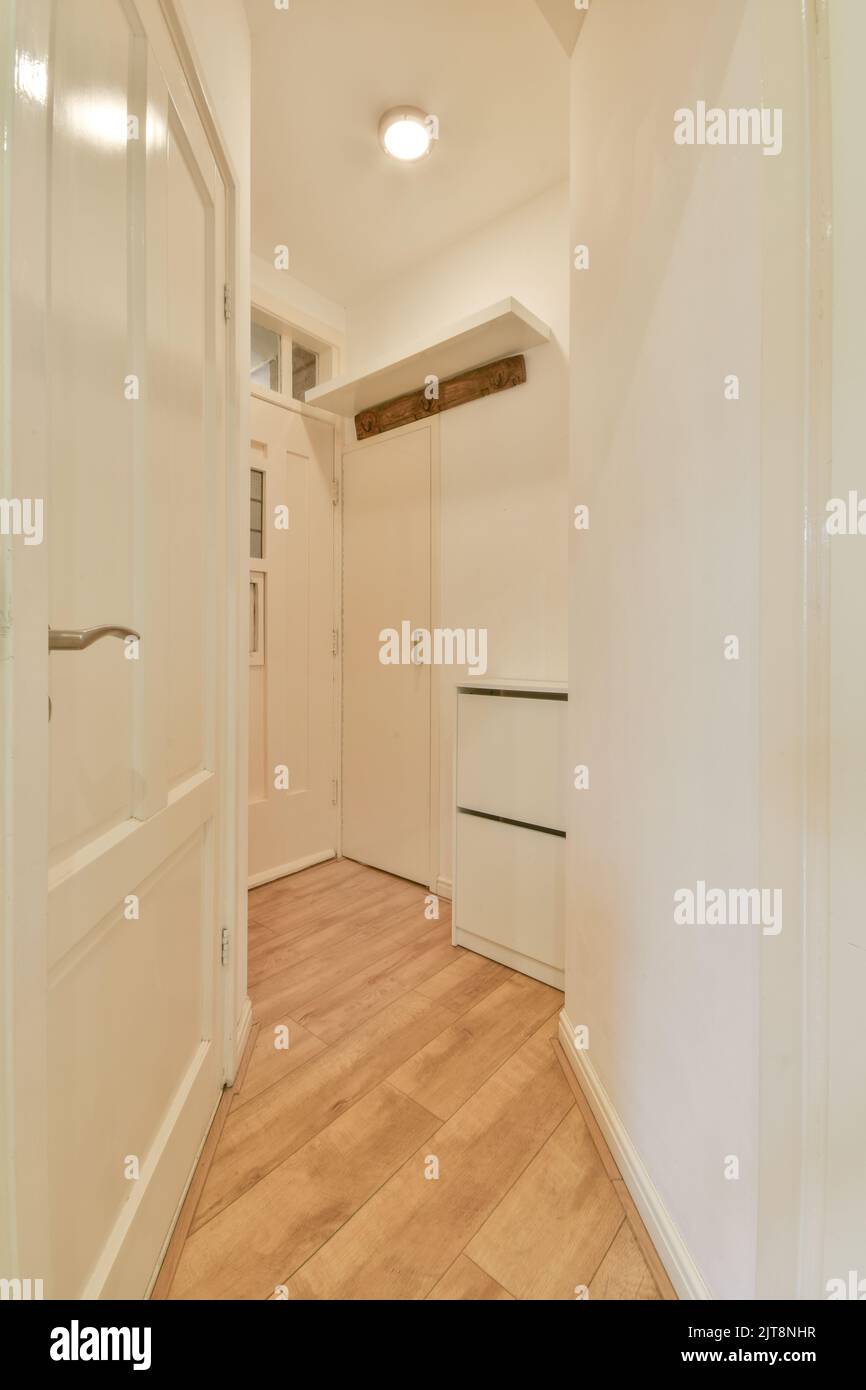 Perspective view of empty narrow hallway with white walls and wardrobe ...