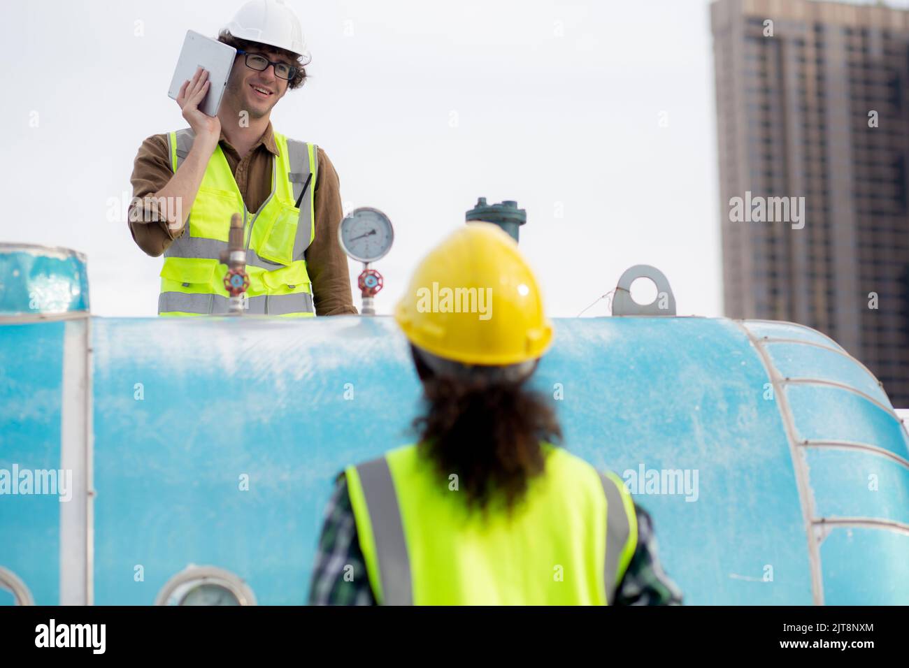 Young woman and man engineer examining pipeline and talking in the ...