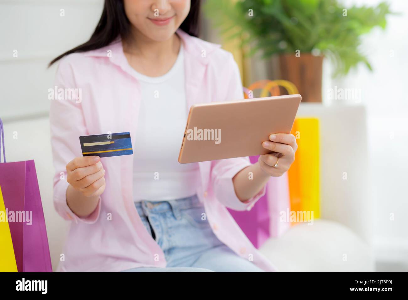 Young asian woman sitting on sofa using digital tablet shopping online ...