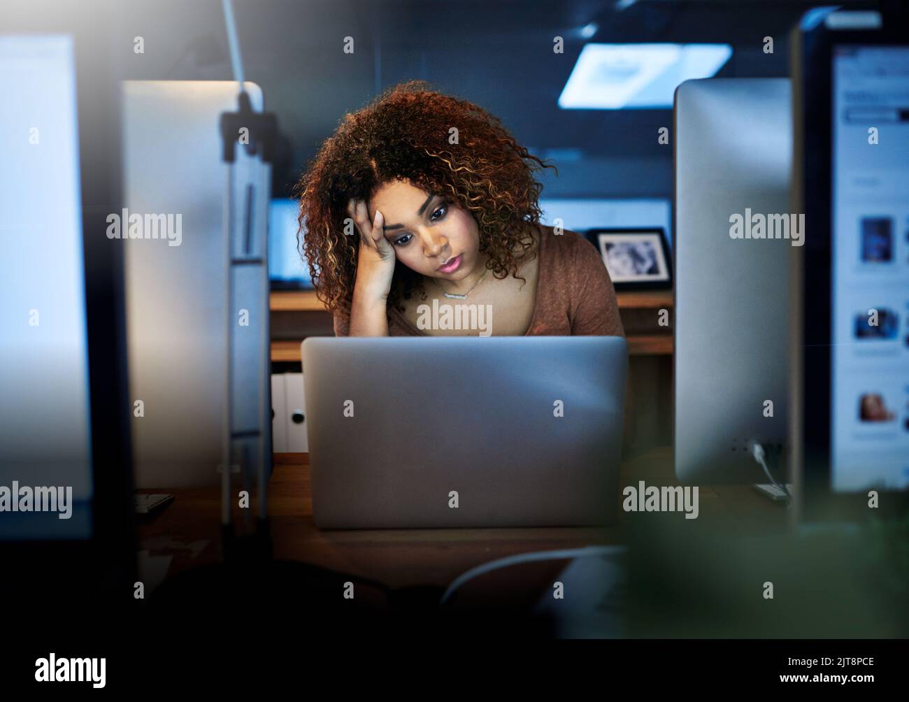 Can I go home yet. a young woman working late in an empty office Stock ...