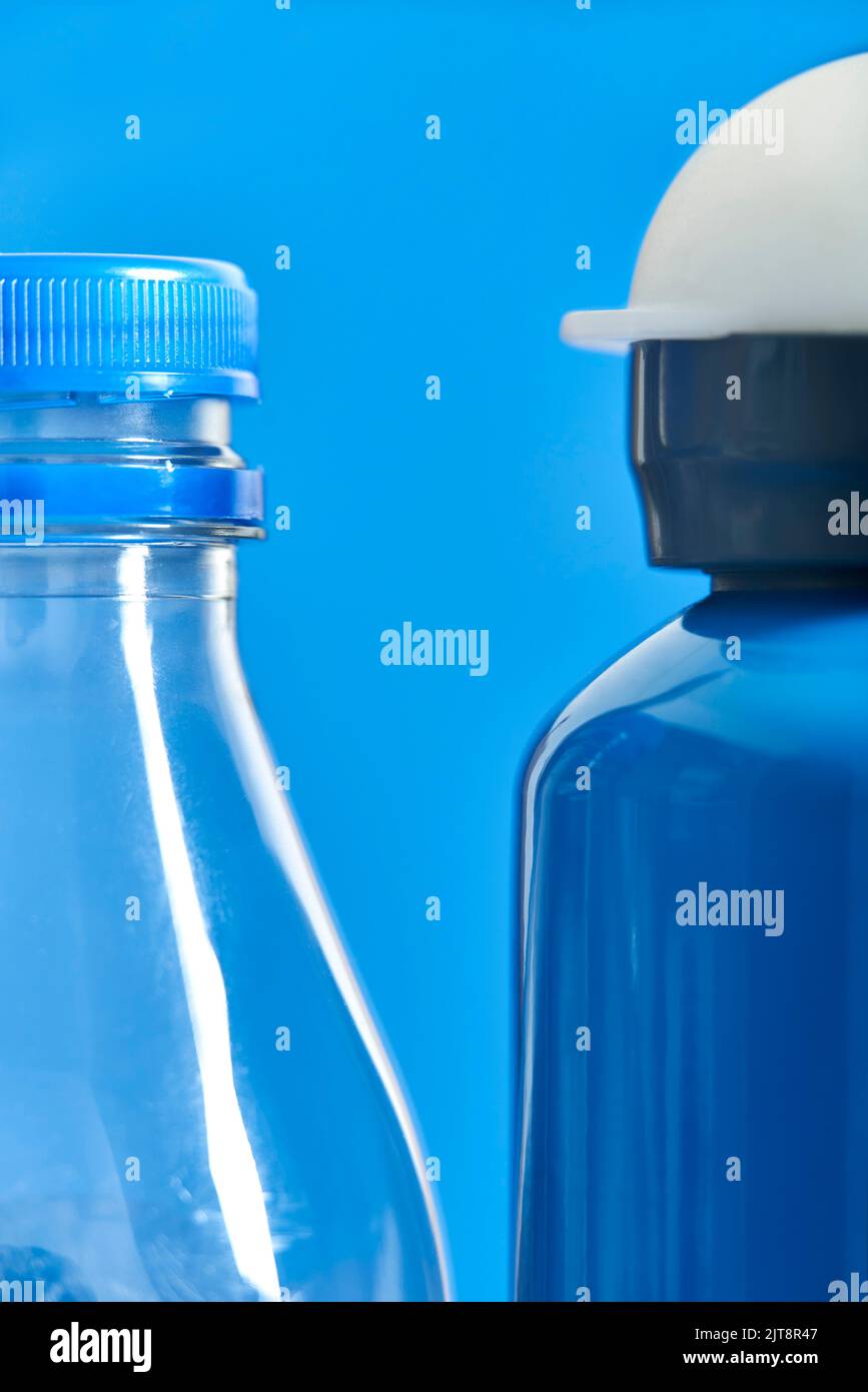 Pair of bottles, a plastic transparent disposable one and a blue metal ...