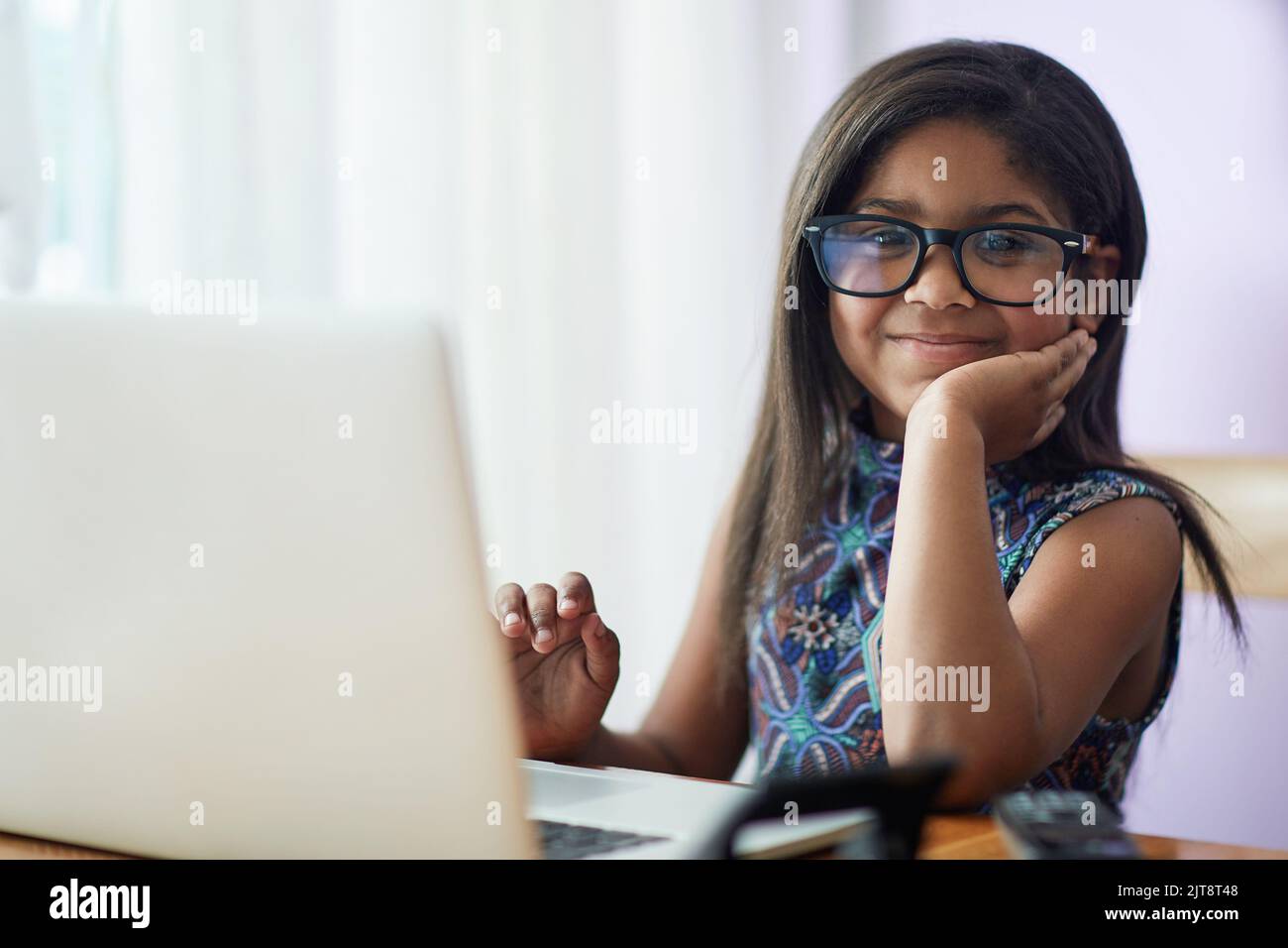 Clever cutie. Portrait of a cute little girl using a laptop in her ...