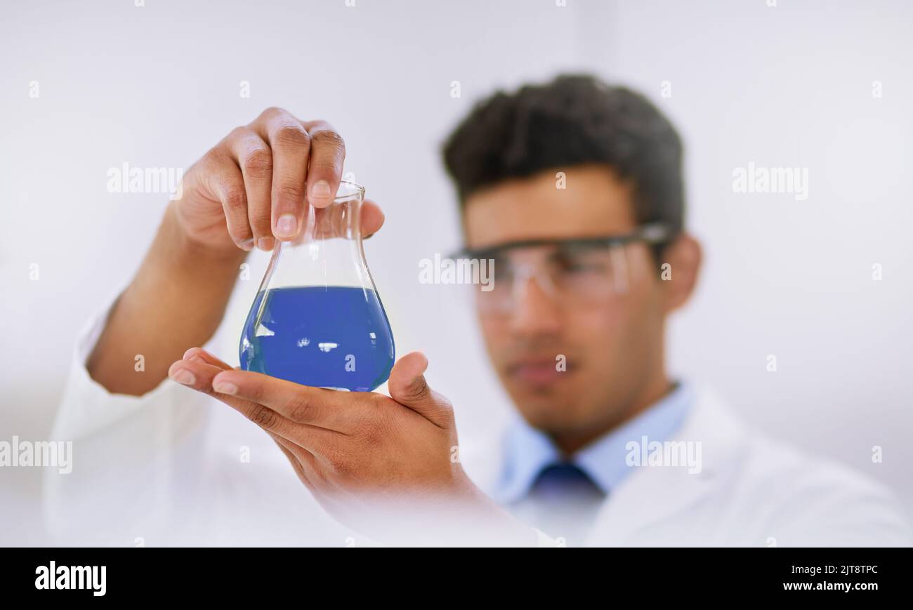 Finding cures in the lab. a lab technician examining a beaker of blue ...
