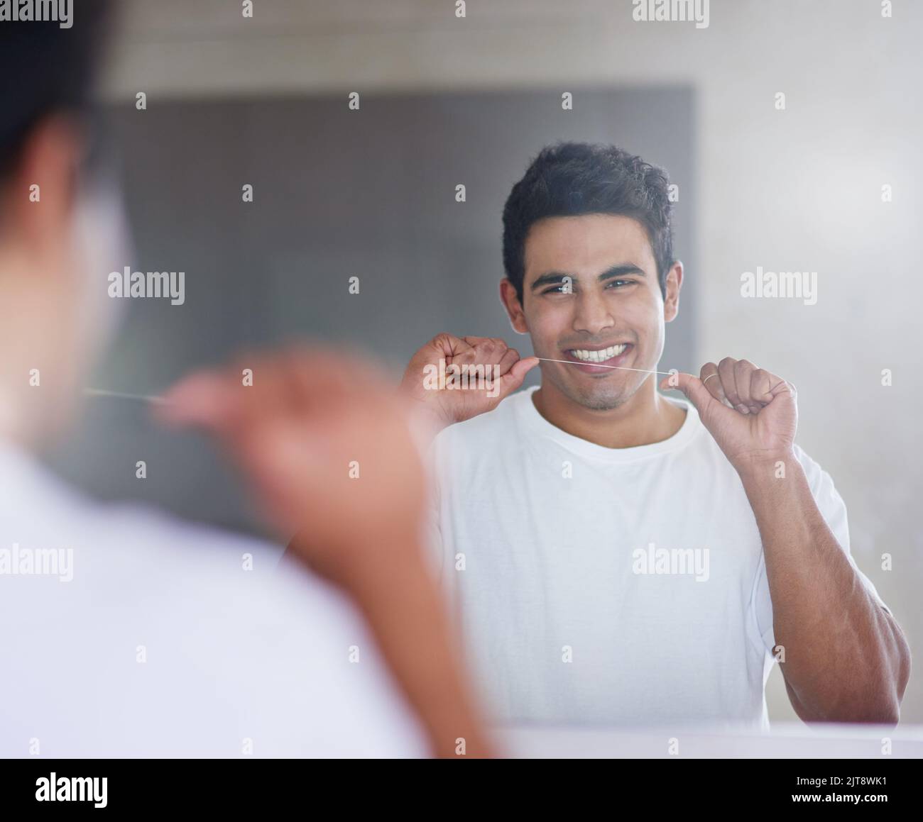 Flossing for a complete clean. a happy young man flossing his teeth at ...