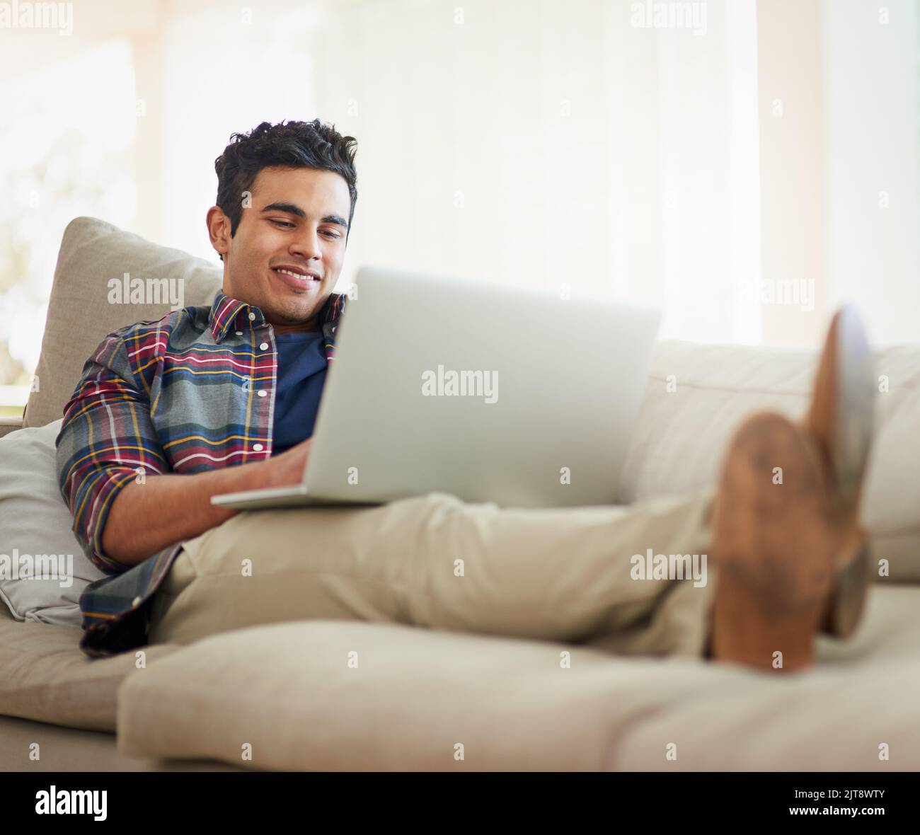 Connected from the comfort of his own couch. a handsome young man using ...