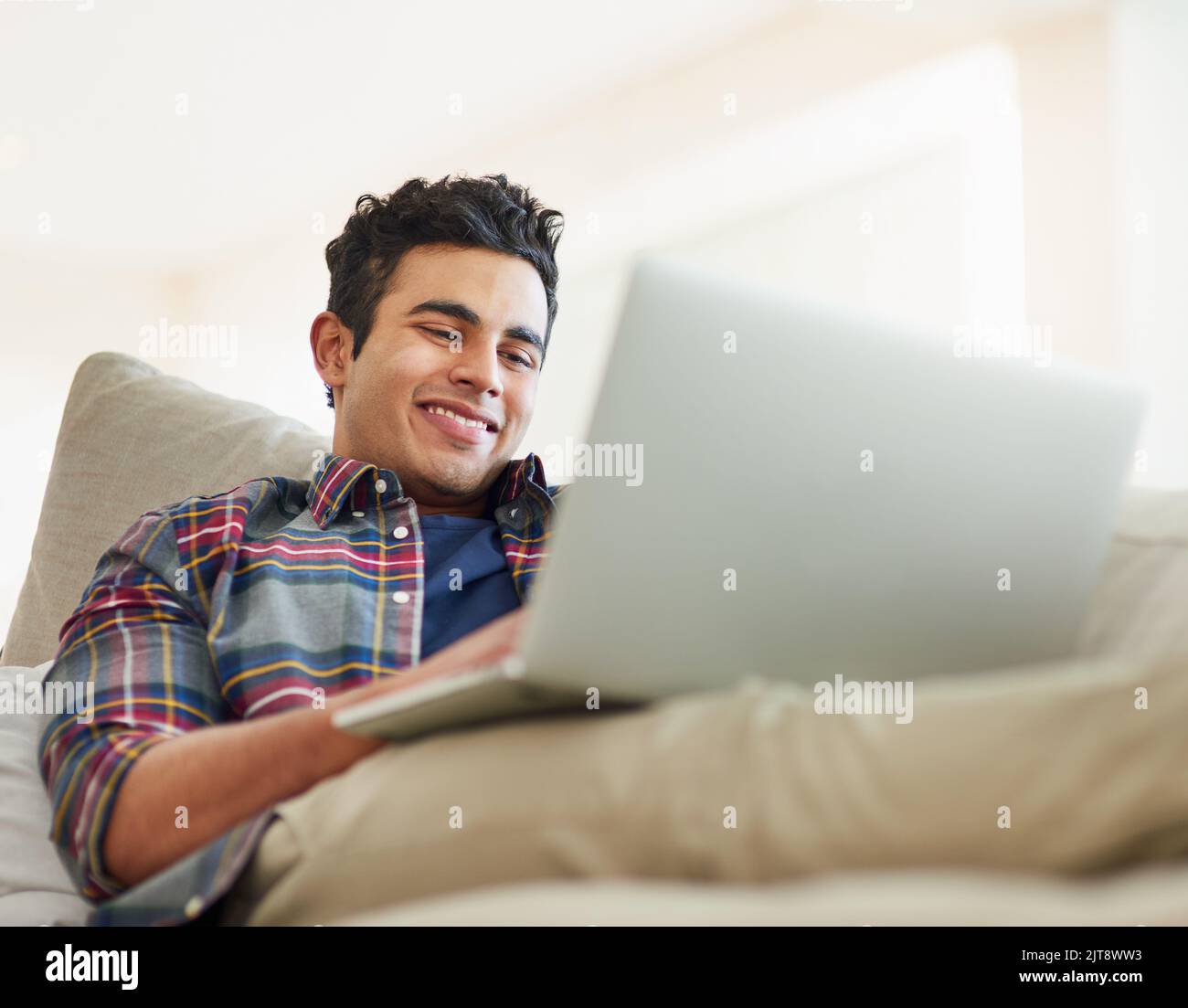 Time to update that status. a handsome young man using his laptop while ...