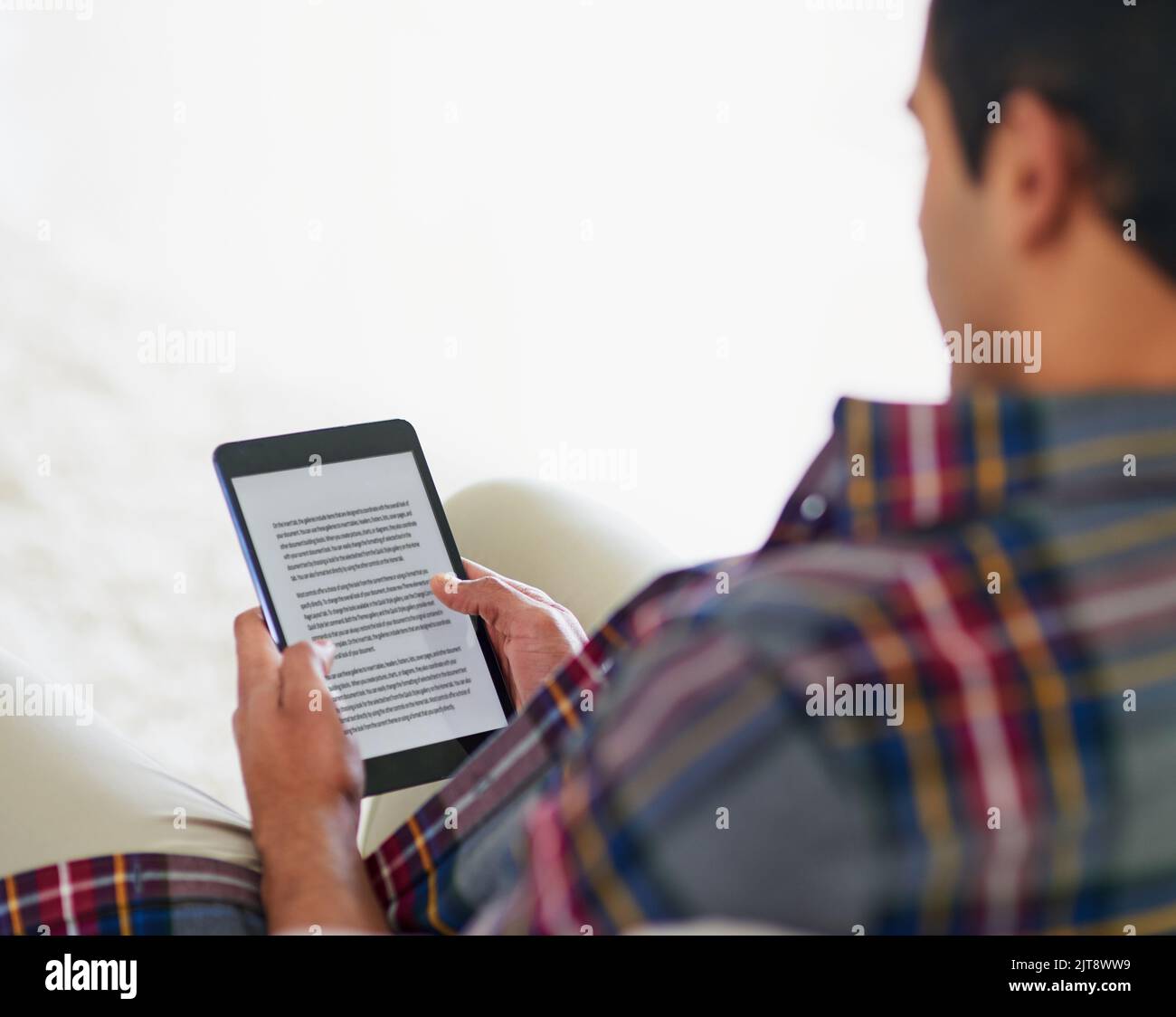 Reading a new post. a young man using his tablet while relaxing on the ...