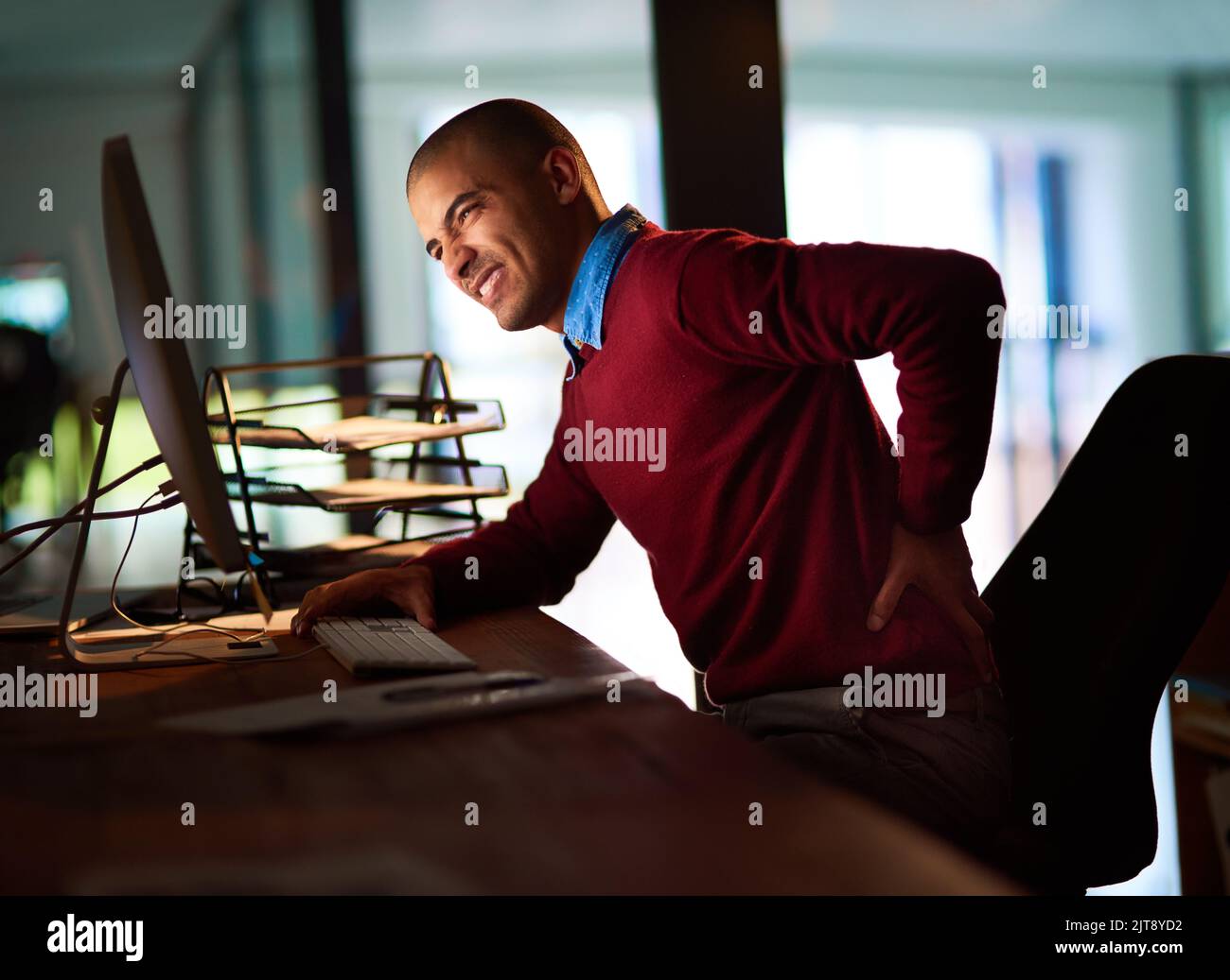 This has been a long shift. a young man holding his back in pain while ...