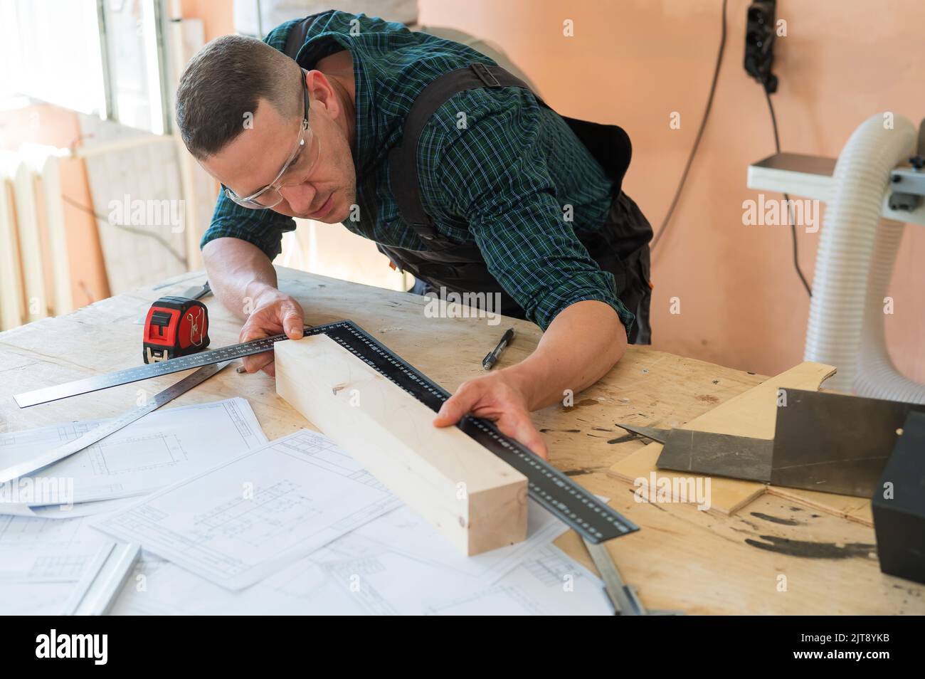 Carpenter measures wooden planks in the workshop Stock Photo - Alamy