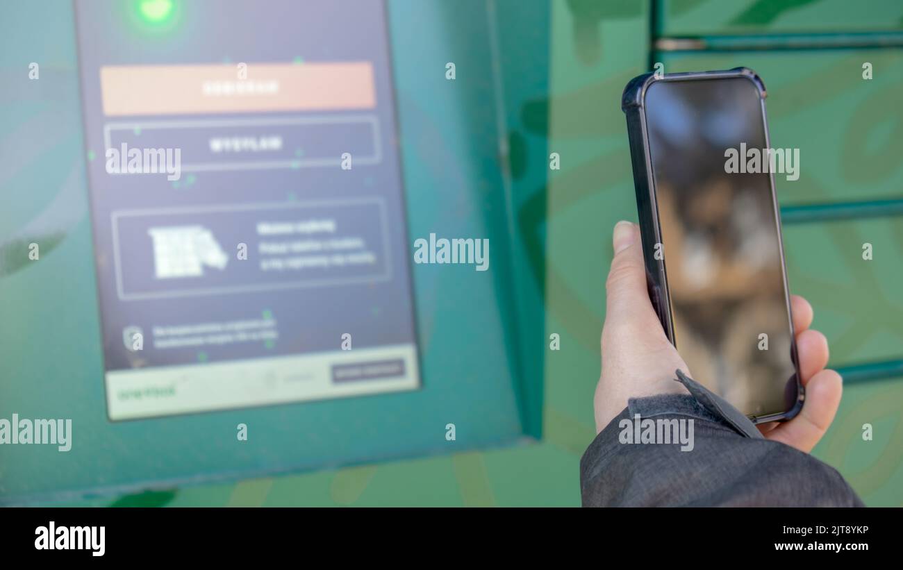 Female hand holding mobile phone next to Parcel locker Collecting ...