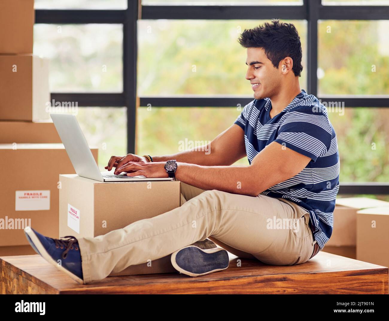 Setting up the wifi in his new pad. a young man using a laptop while ...
