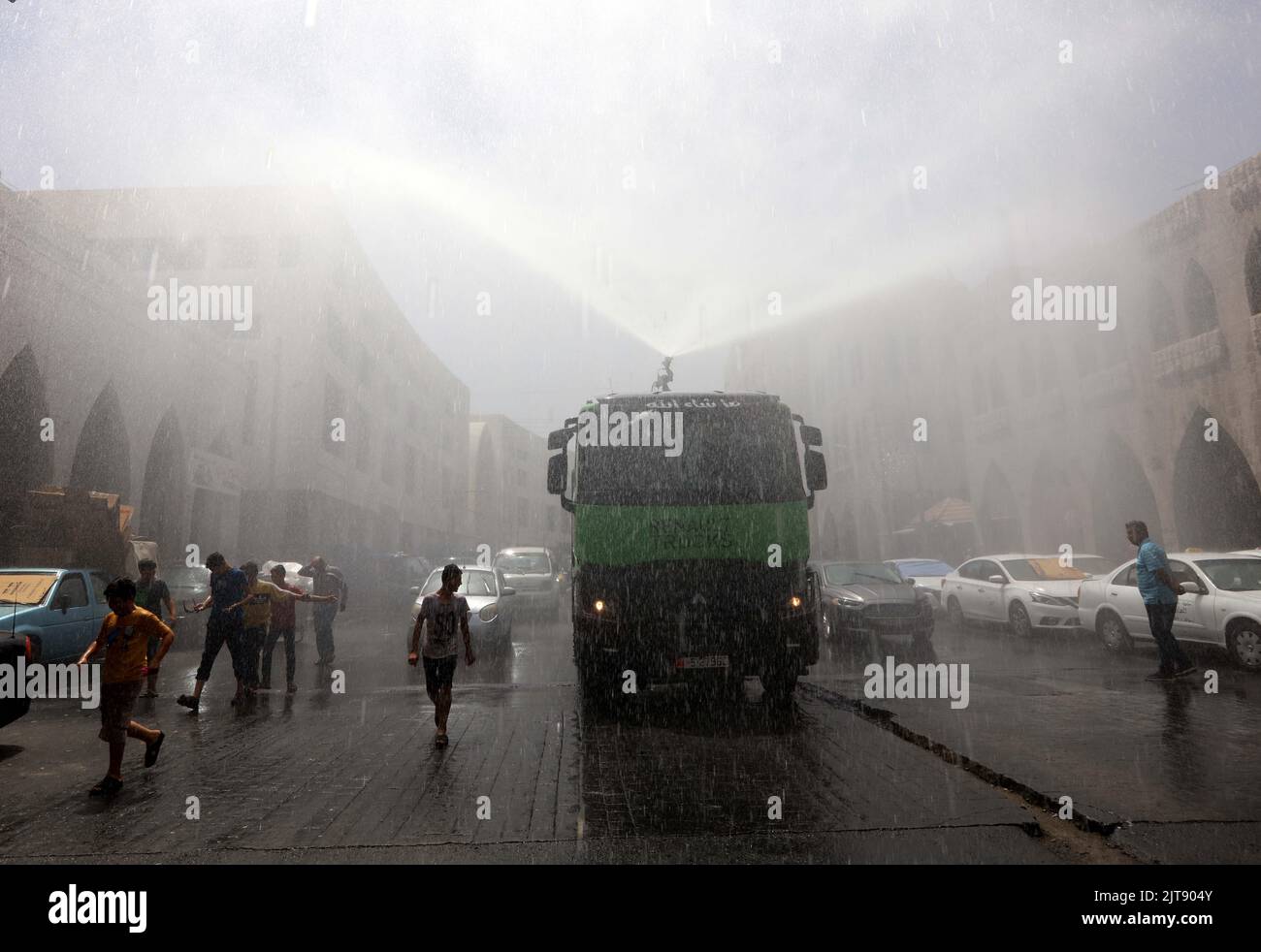 Amman, Jordan. 28th Aug, 2022. People cool off in a spray of water from ...