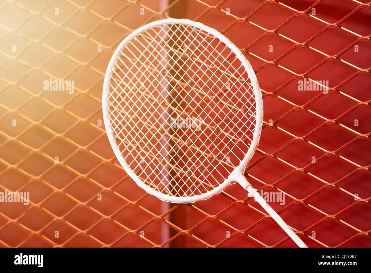 one badminton racket is hung on red grill by a cable tie for display in ...