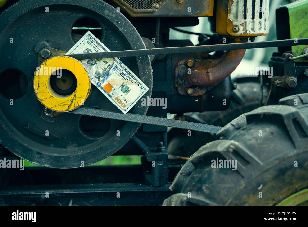 A hundred dollar bill lies on the engine of a small rural walk-behind ...