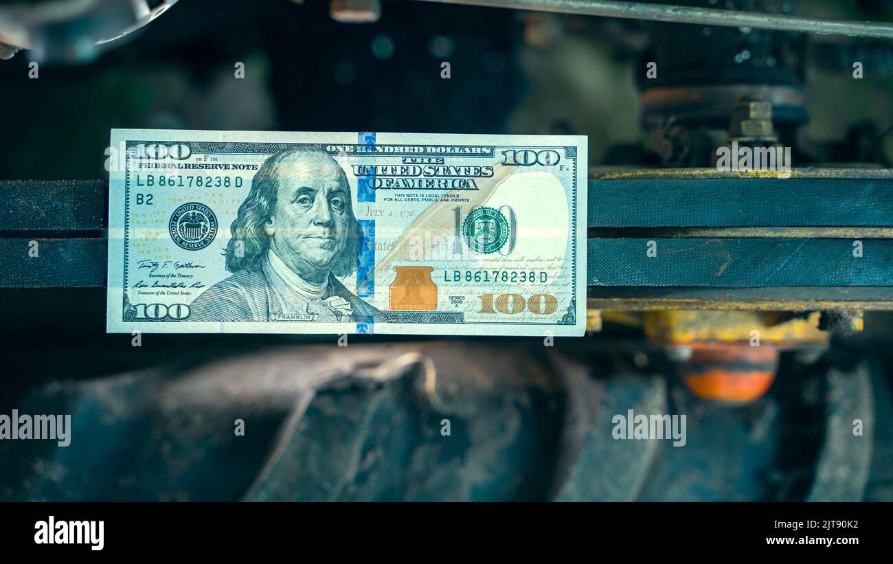 A hundred dollar bill lies on the engine drive belts of a rural walk ...