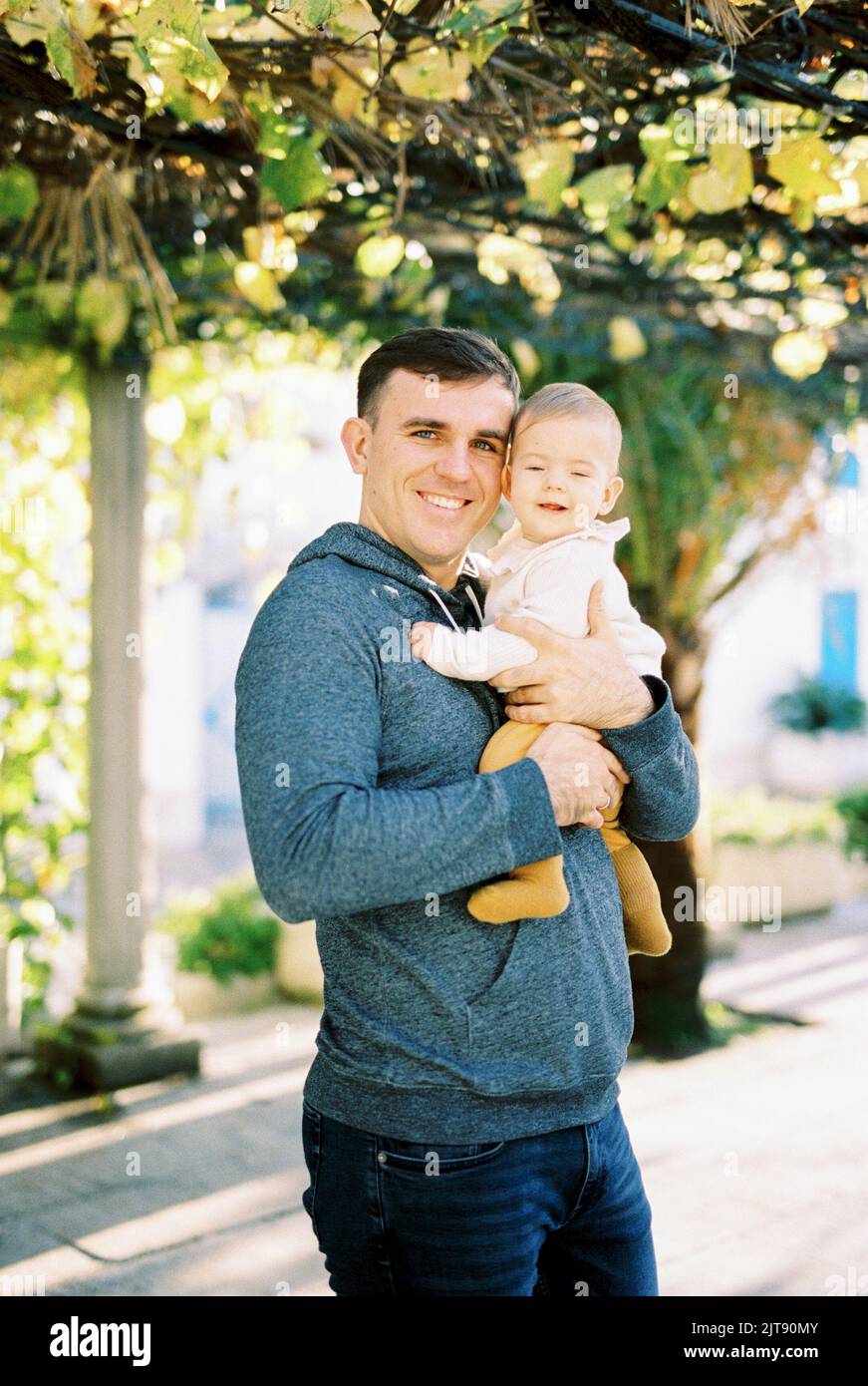 Smiling dad with a baby in his arms stands in the yard Stock Photo - Alamy