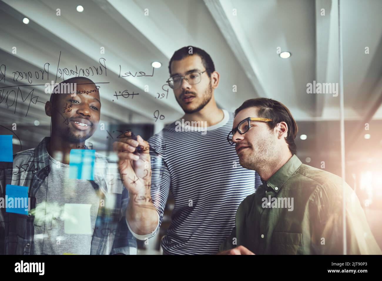 Plan first, act later. a group of young designers planning on a glass ...
