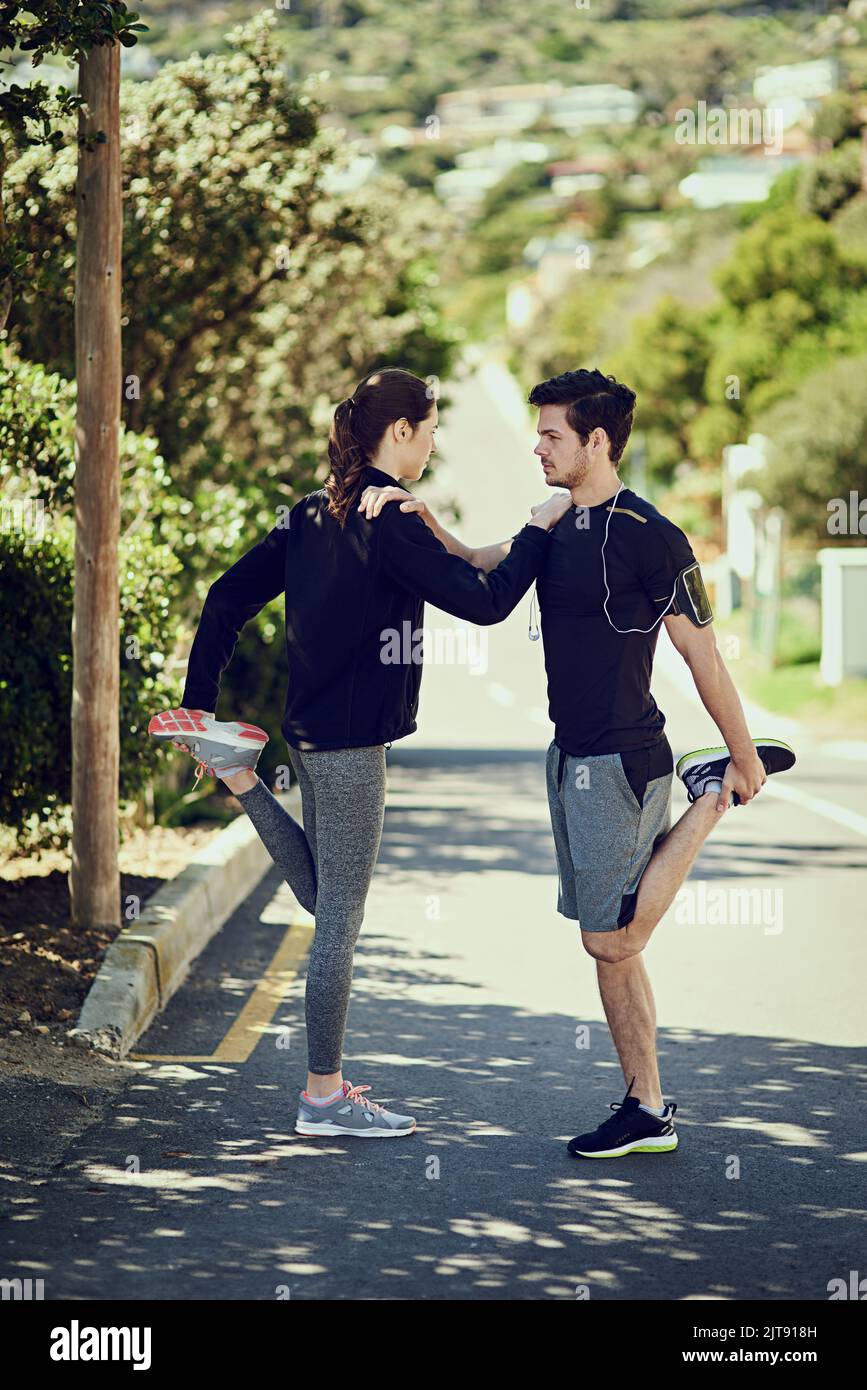 Supporting one another. Full length shot of two young people warming up ...