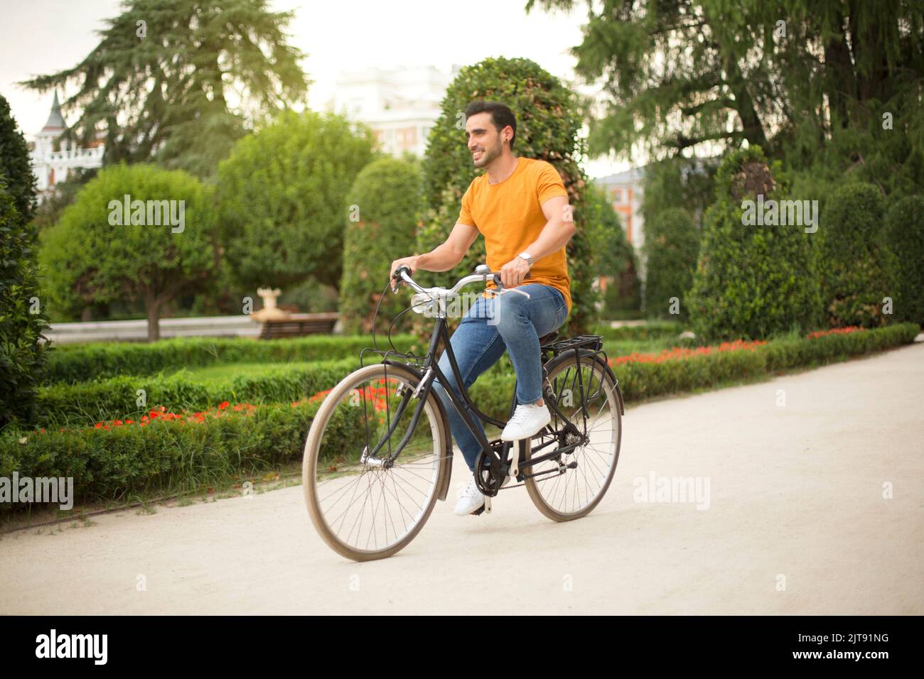 Caucasian smiley man driving a vintage bike along a sandy path in a ...