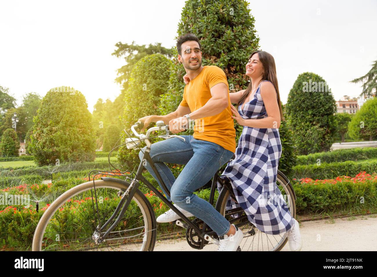 Romantic scene of a couple riding a bike during sunset in a park Stock ...
