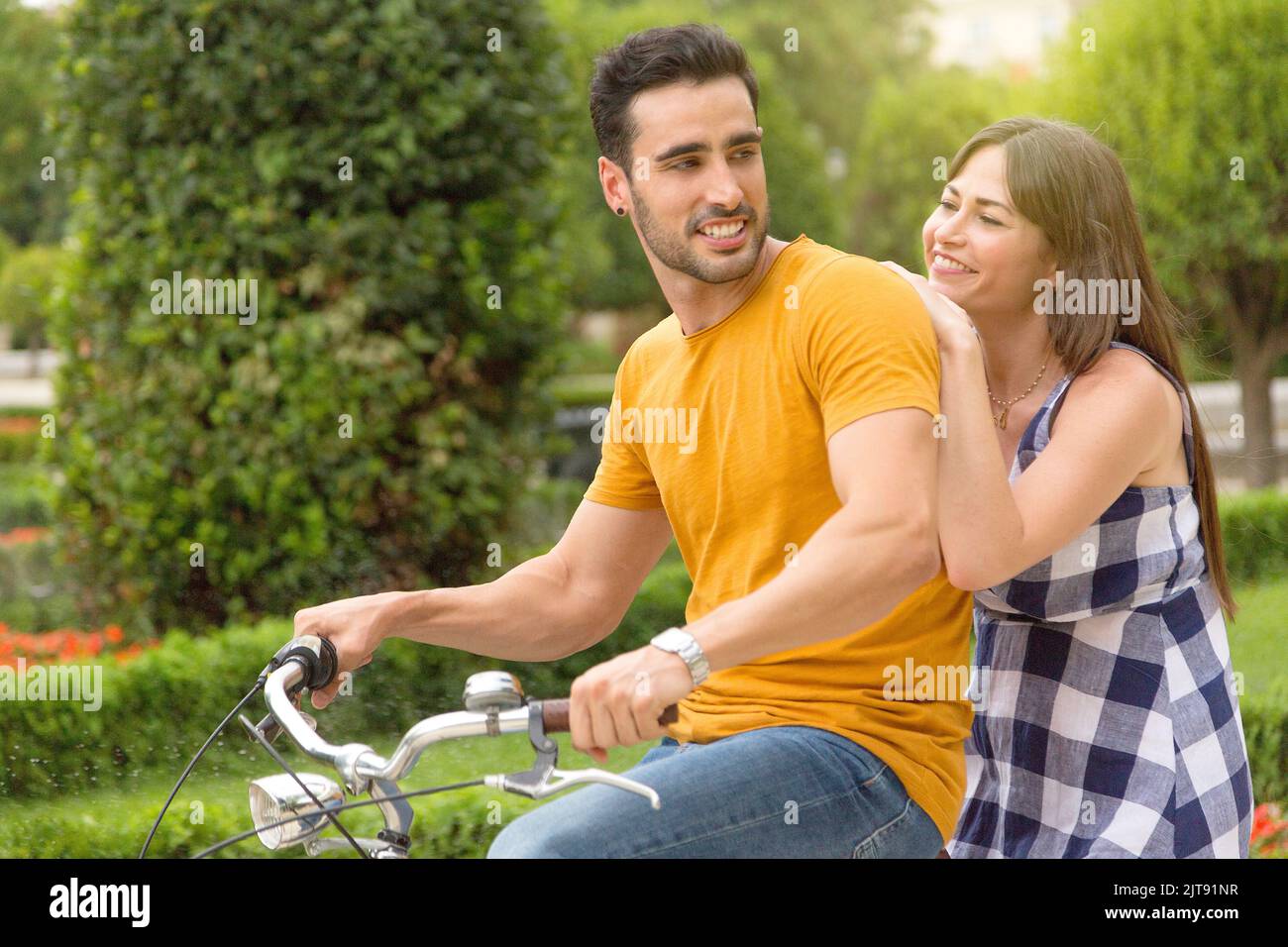 Romantic scene of a caucasian couple riding a bike during sunset in a ...