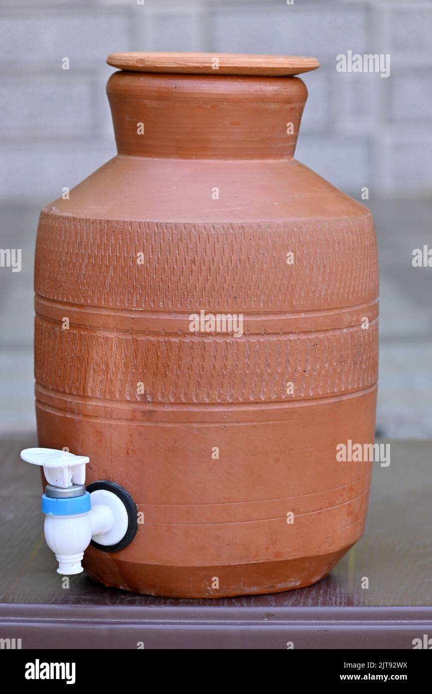 A vertical closeup of a brown earthen clay pot filter with a tap Stock ...