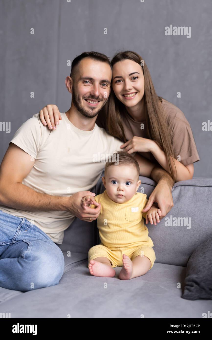 Cheerful family are spending funny time while sitting on divan in room ...