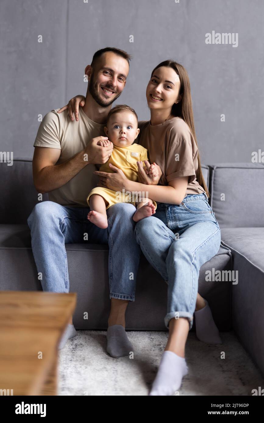 Happy young Caucasian family with small son relax on sofa in living ...