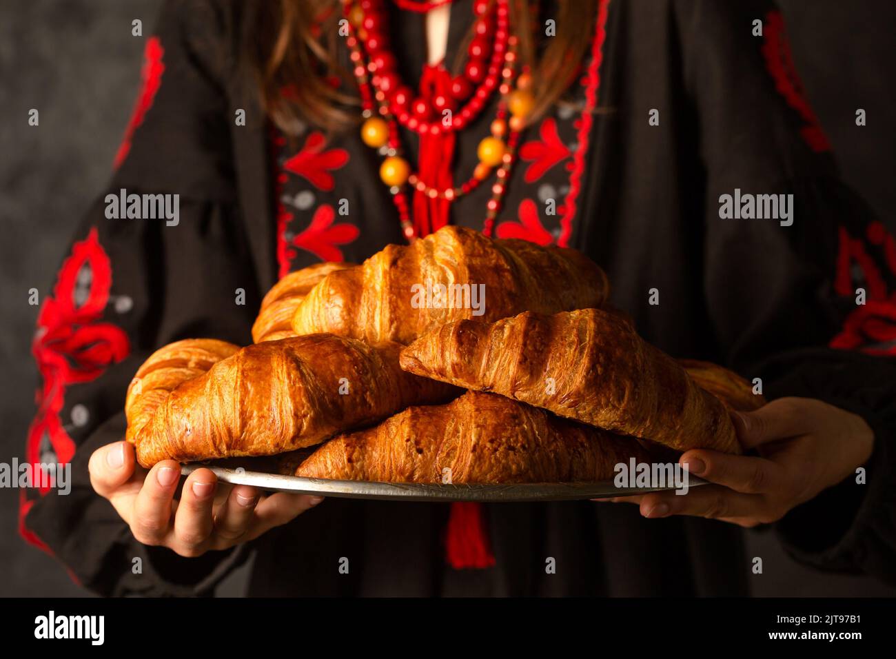 Crispy croissants in the hands of a Ukrainian woman in an embroidered ...