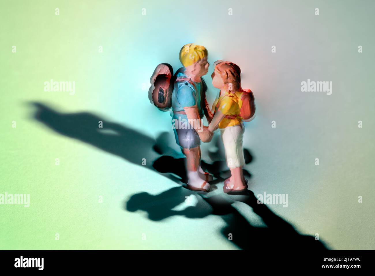 Miniature young couple wearing backpacks in love standing holding hands ...