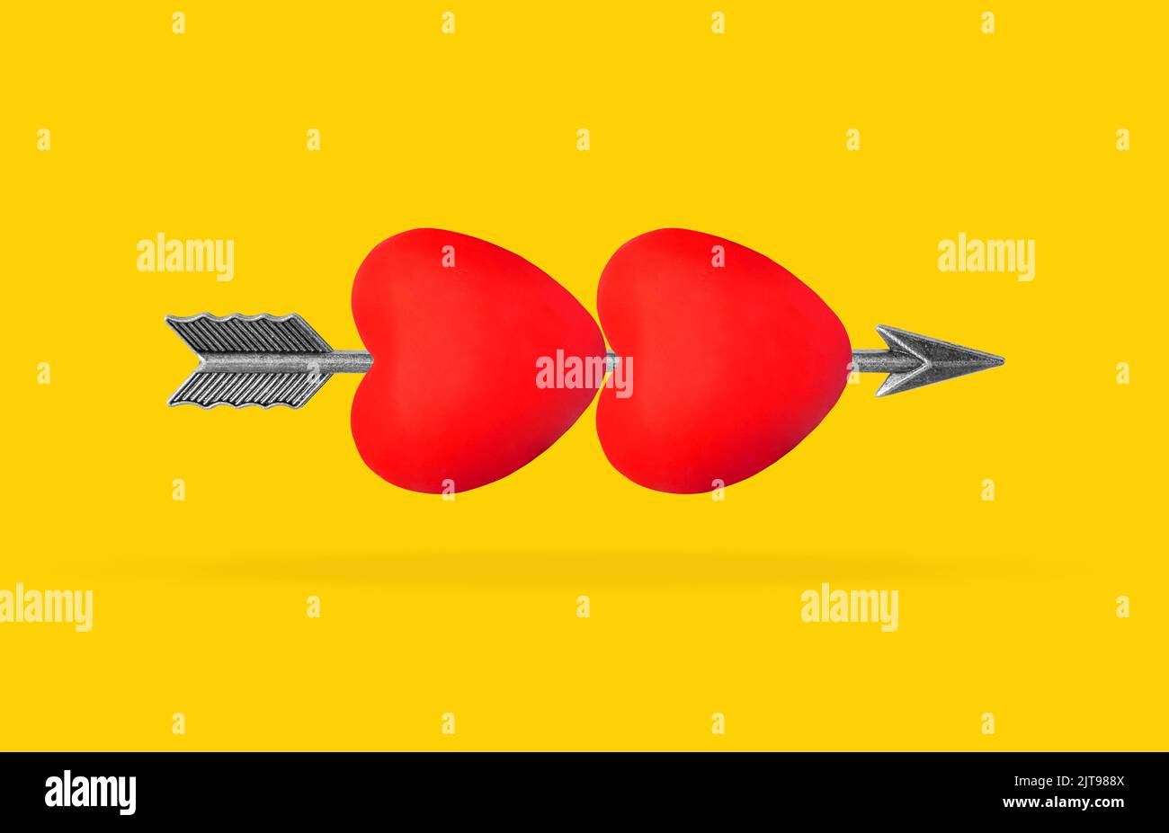 Feathered arrow passing through two red hearts isolated on yellow ...